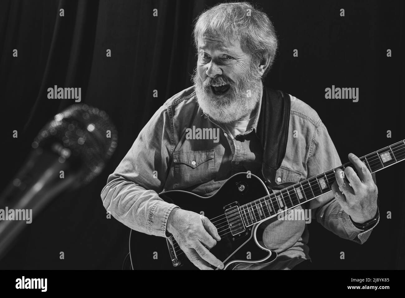 Black and white portrait of stylish old man, rock musician playing ...