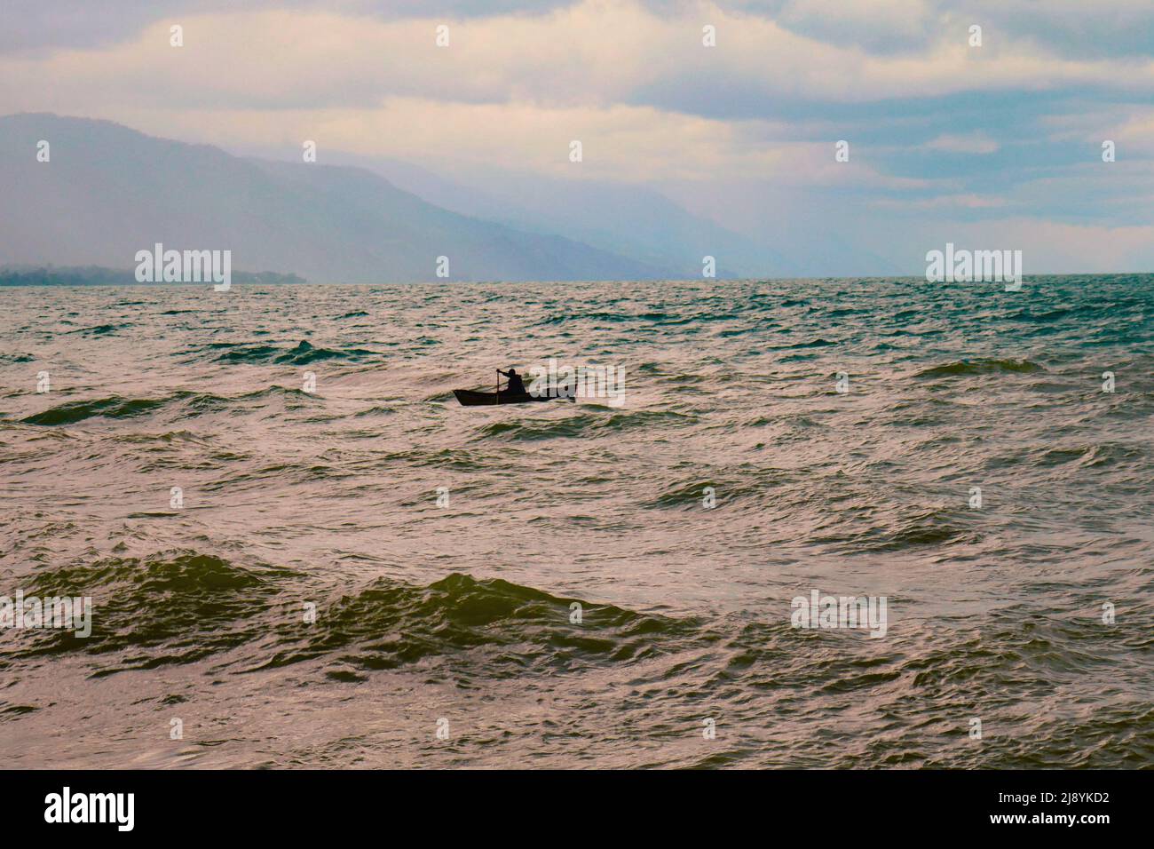 A fisherman at Matema Beach, Lake Nyasa against a golden sunset ...