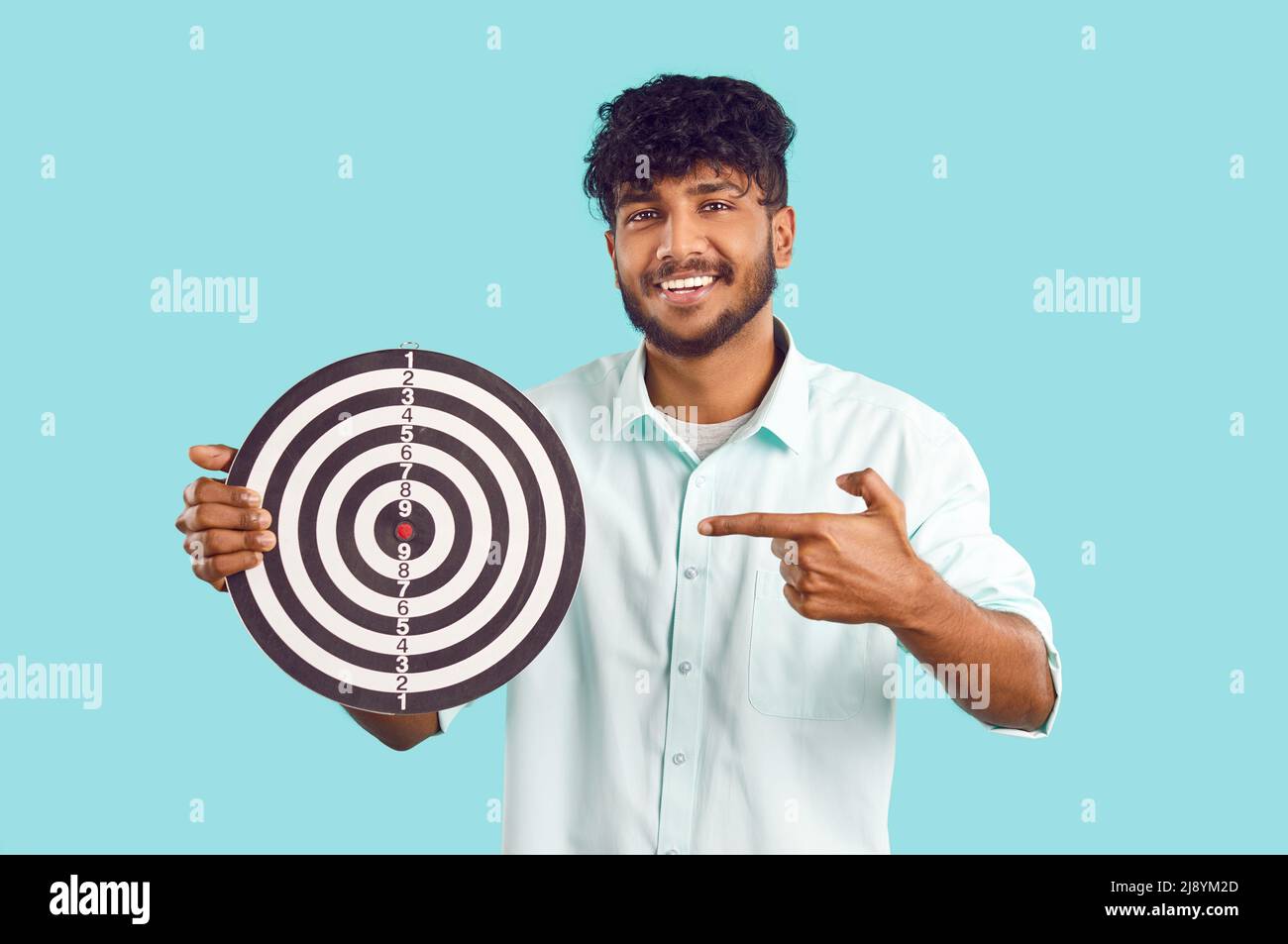 Portrait of smart and positive Hindu man with darts board that ...