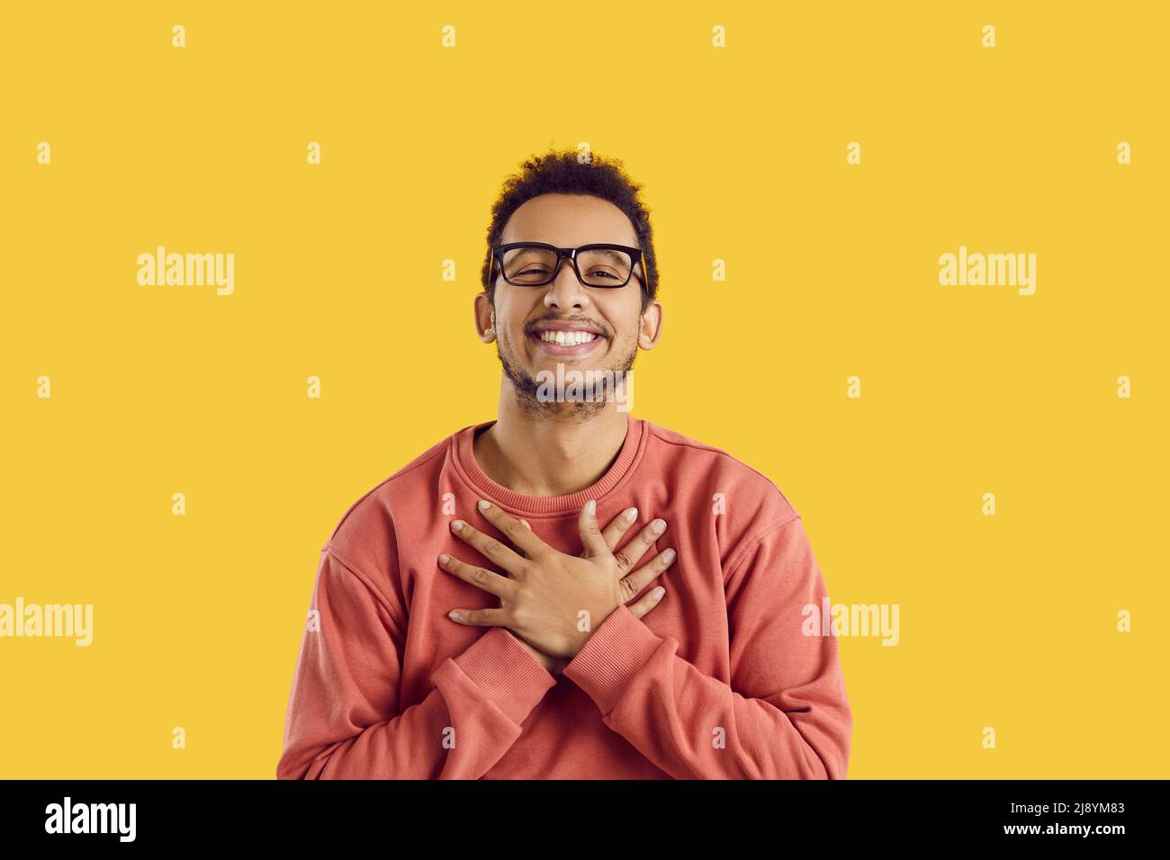 Happy grateful black man holding his hands on his chest, smiling and ...