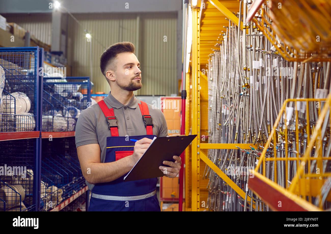 Young man who works as a salesman at a hardware store checking goods in ...