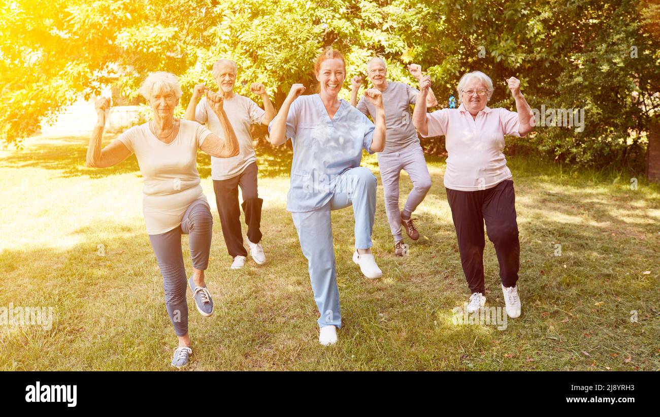 Happy group of seniors doing aerobics training with geriatric nurse in ...