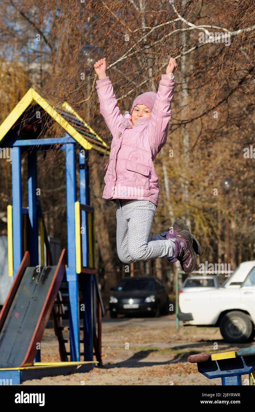 Little girl jumping high on playing a children playground. November 23 ...