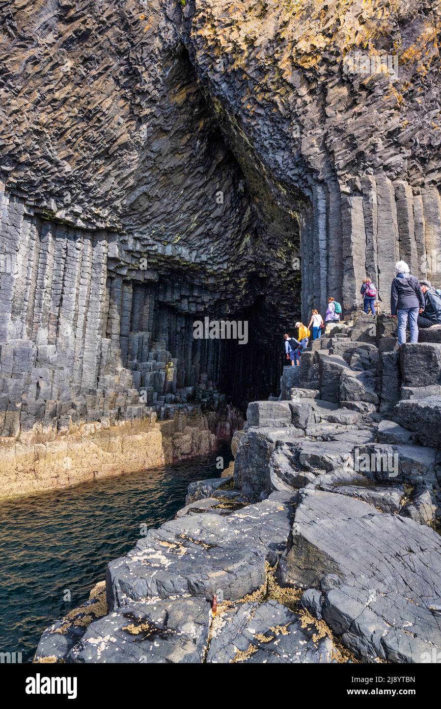 Sightseers scramble over rocks at the entrance to Fingal’s Cave on the ...