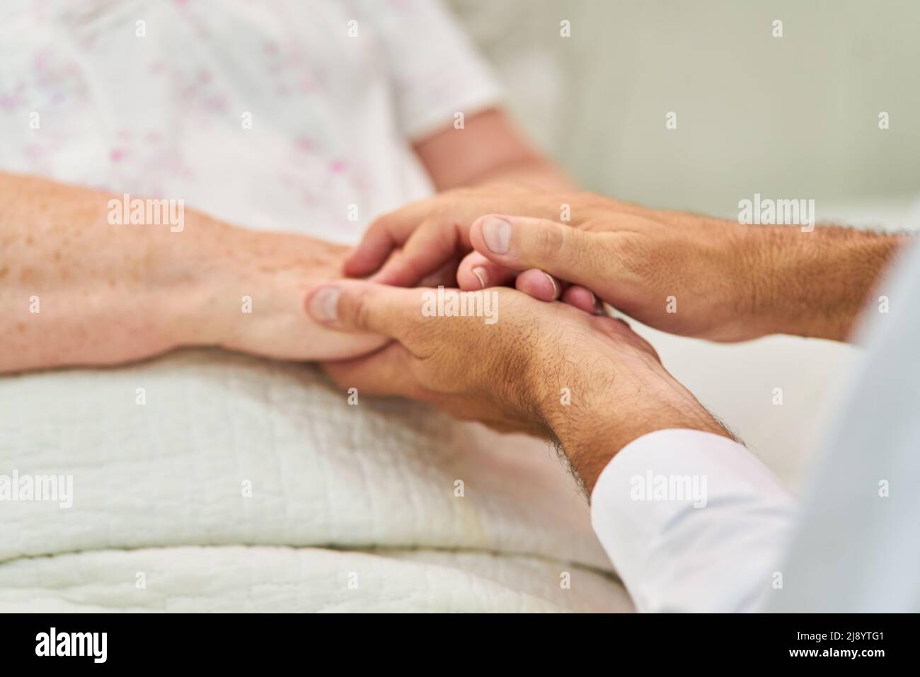 Man holding hands to comfort seniors in hospice Stock Photo - Alamy