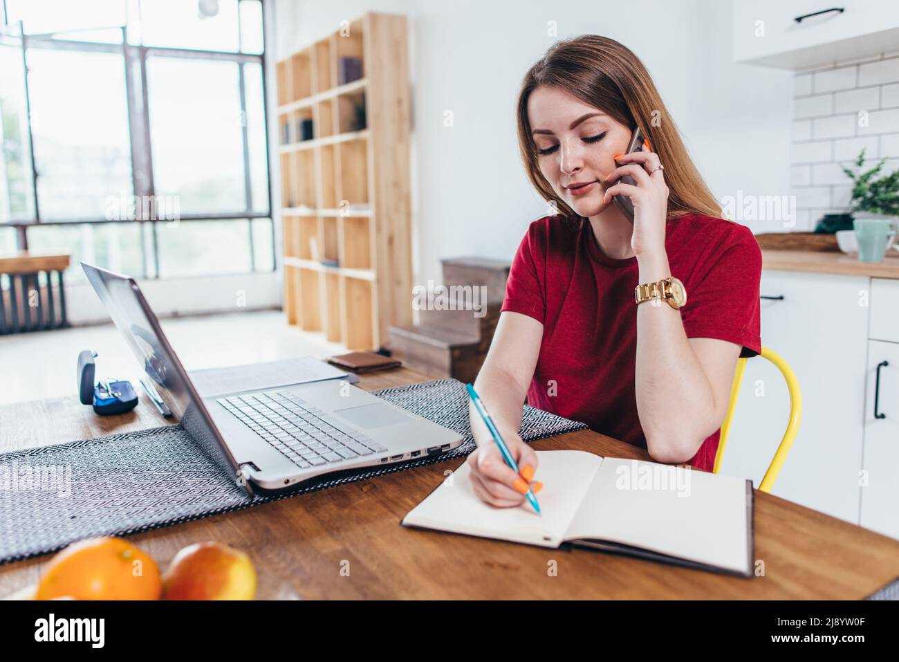 Woman working at home write notes while talking on phone Stock Photo ...