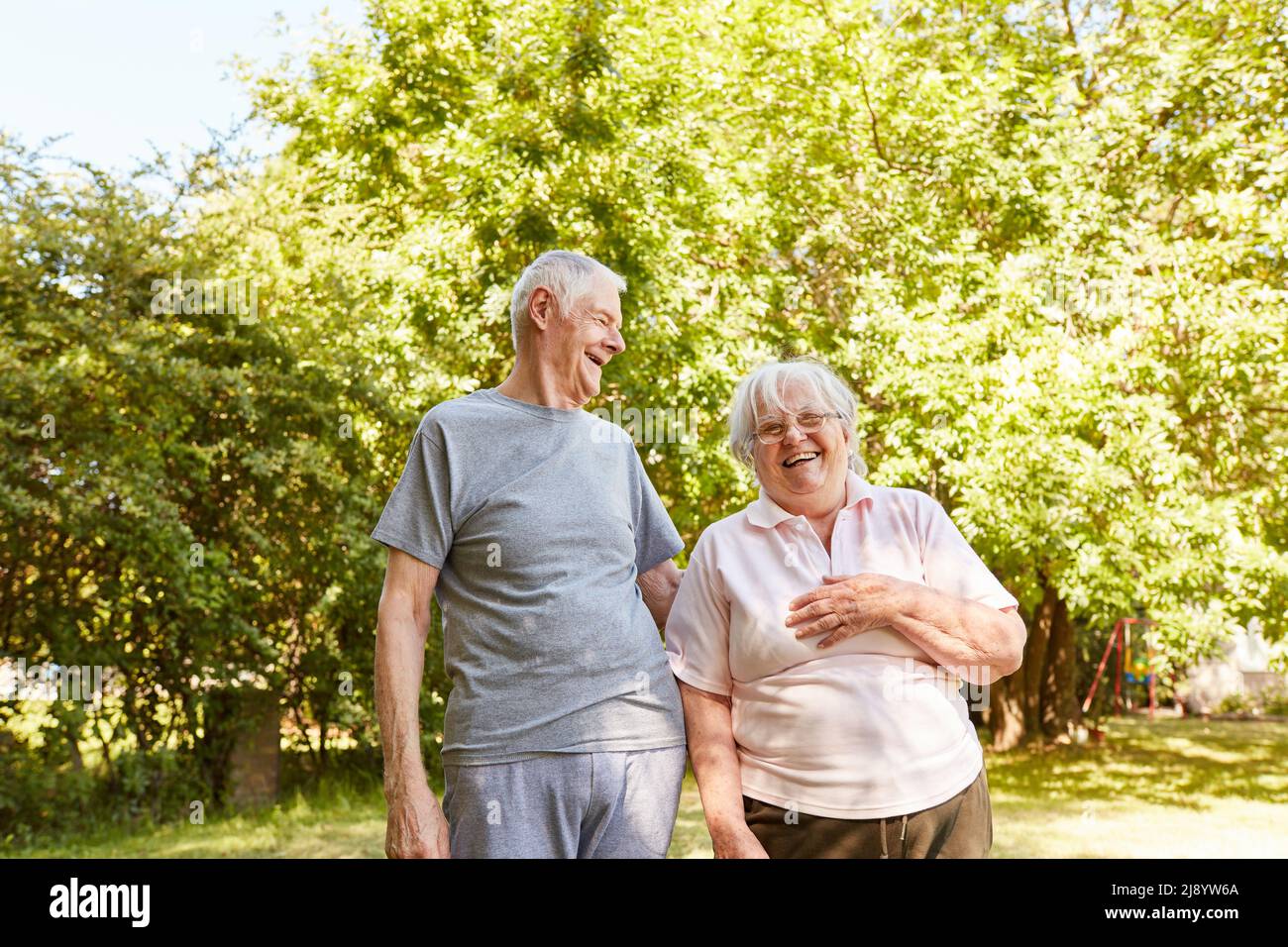Senior couple on a walk in summer in nature has fun and laughs at a ...