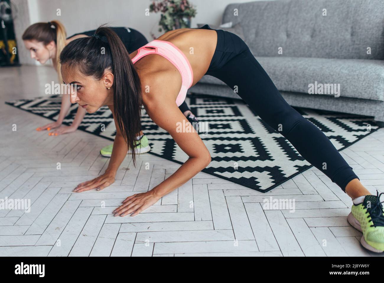 Two Fit Girls Doing Home Workout Performing Lateral Lunges At Home