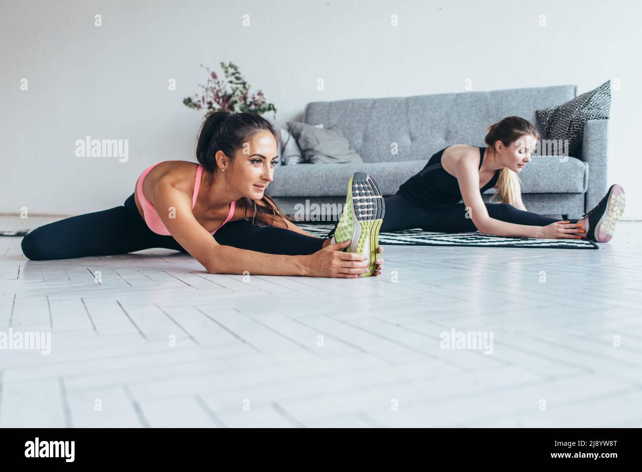 Sportswomen warming-up muscles before workout doing stretching exercise ...