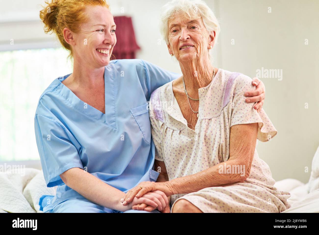 Caring geriatric nurse hugging and comforting old woman in nursing home ...