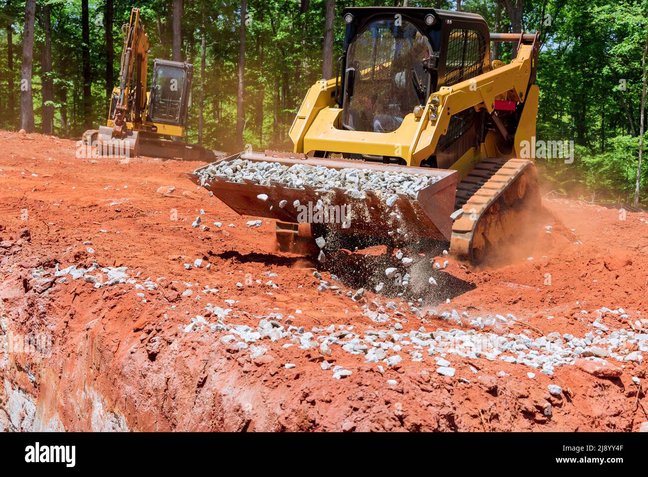 An excavator bucket rakes in crushed stone the excavator is picking up ...