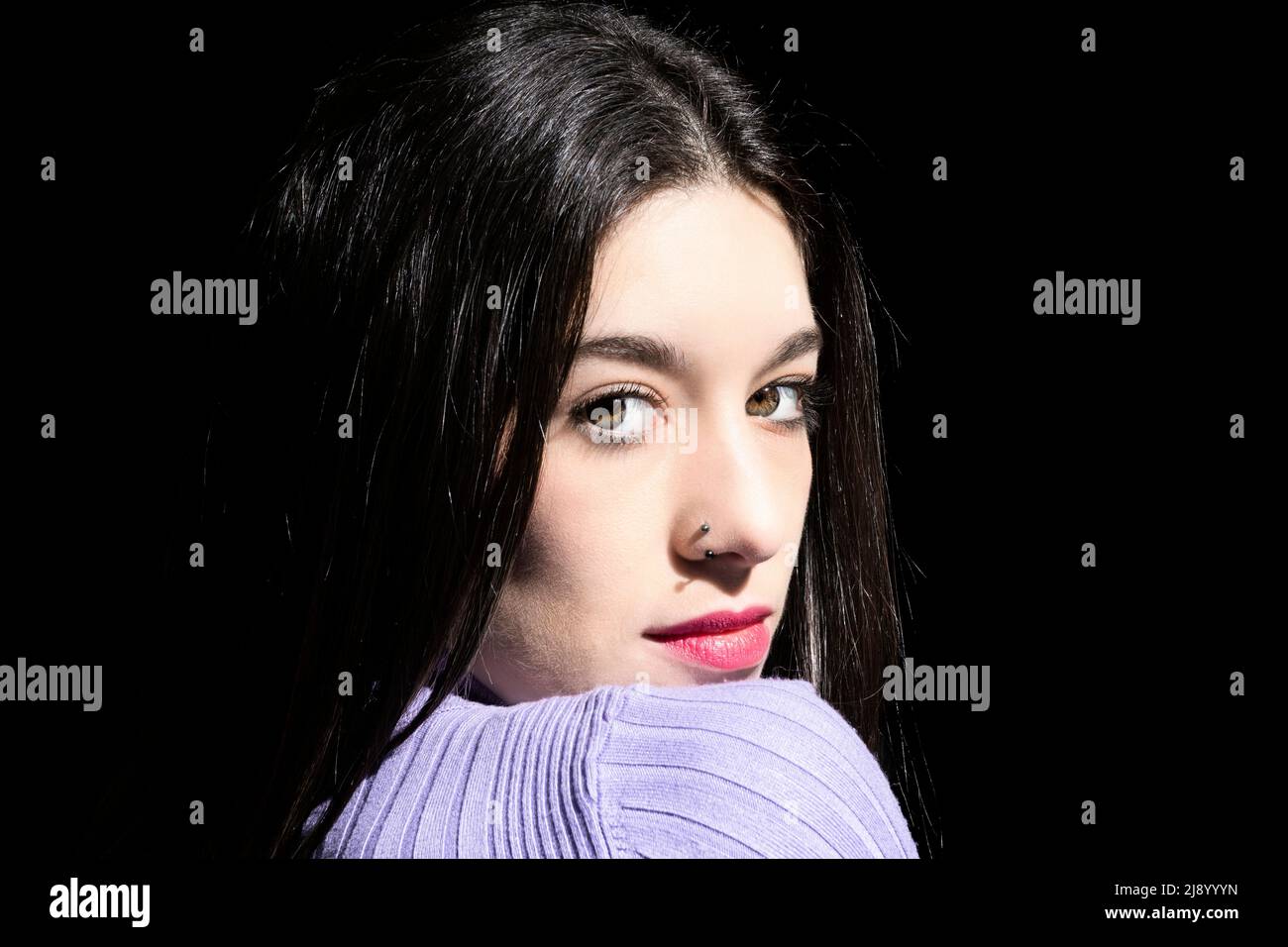 brunette woman looking over her shoulder on black background Stock ...