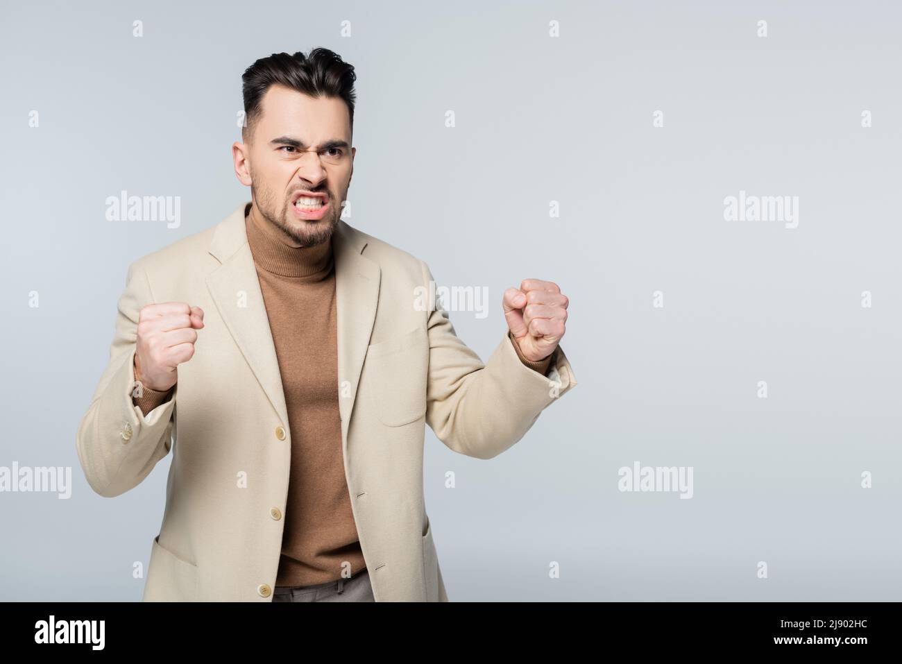 angry critic grimacing and showing clenched fists isolated on grey ...