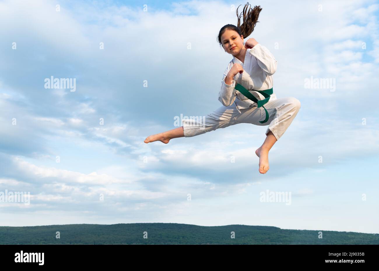 karate girl in kimono jump on sky background Stock Photo - Alamy