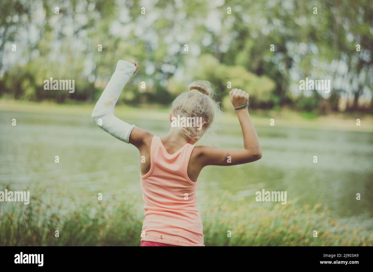 little child with bandage on broken hand standing back view in green ...