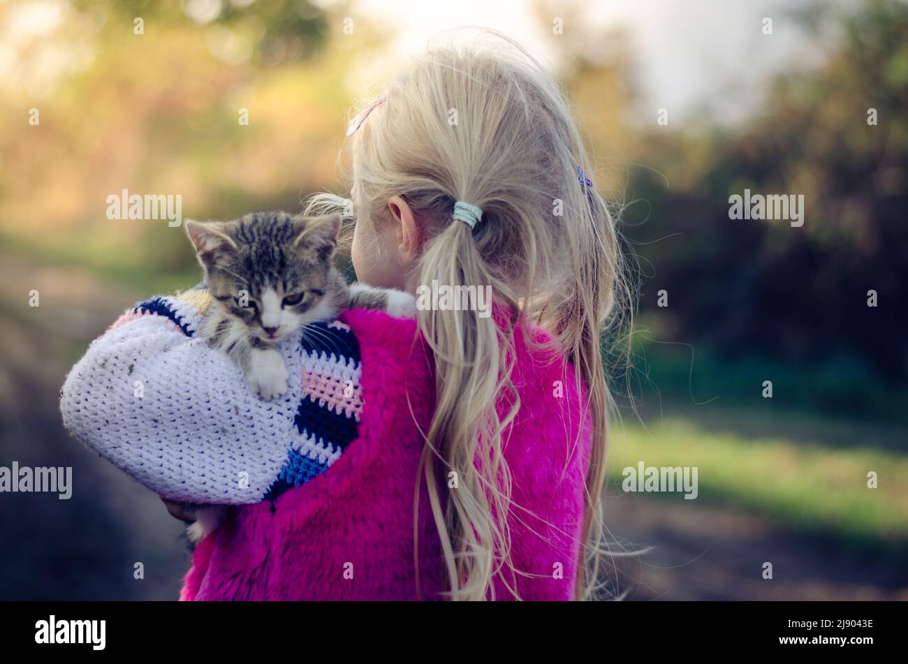 little child with long blond hair holding cute cat back view Stock ...