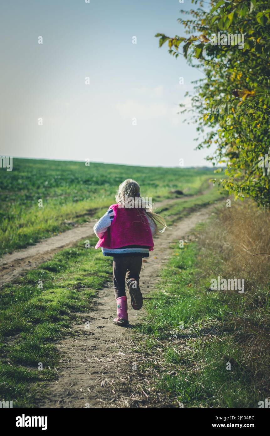 little child back view running away in rural path in autumnal time ...