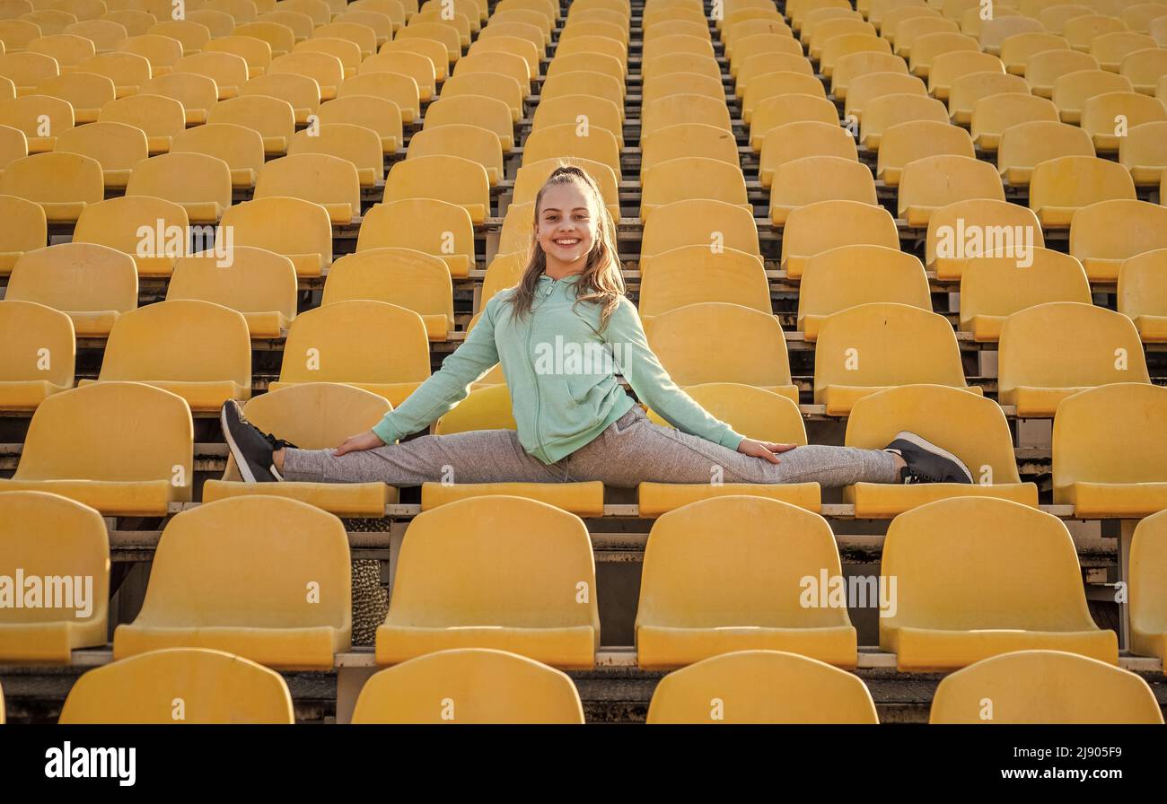 Happy girl gymnast do splits stretching legs on stadium seats ...