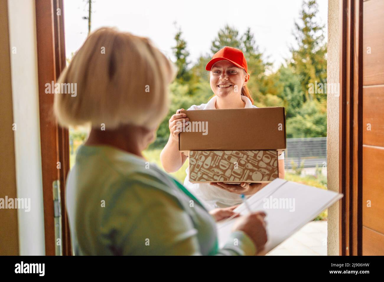 Caucasian delivery woman deliver box parcel package to customer at home ...