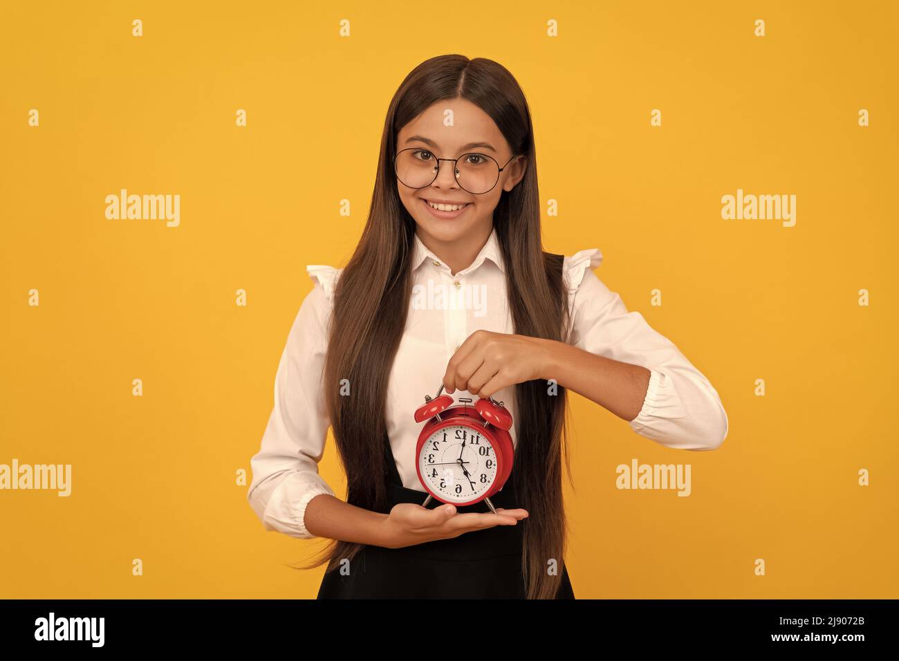 happy nerd child with alarm clock. school kid in uniform and glasses ...