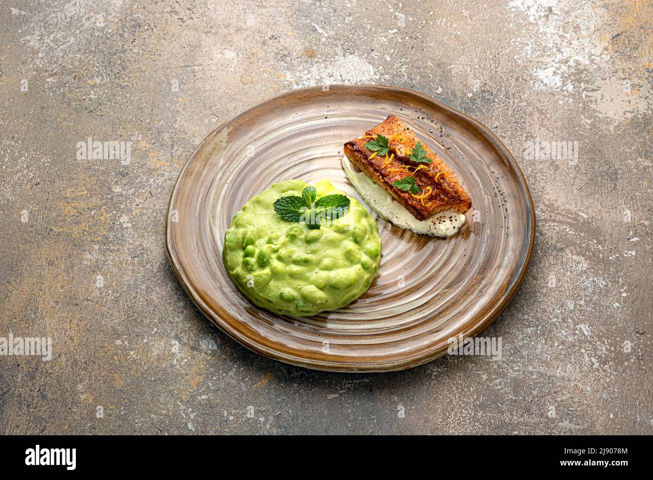 Pan seared white fish fillet with edamame puree on rustic background ...