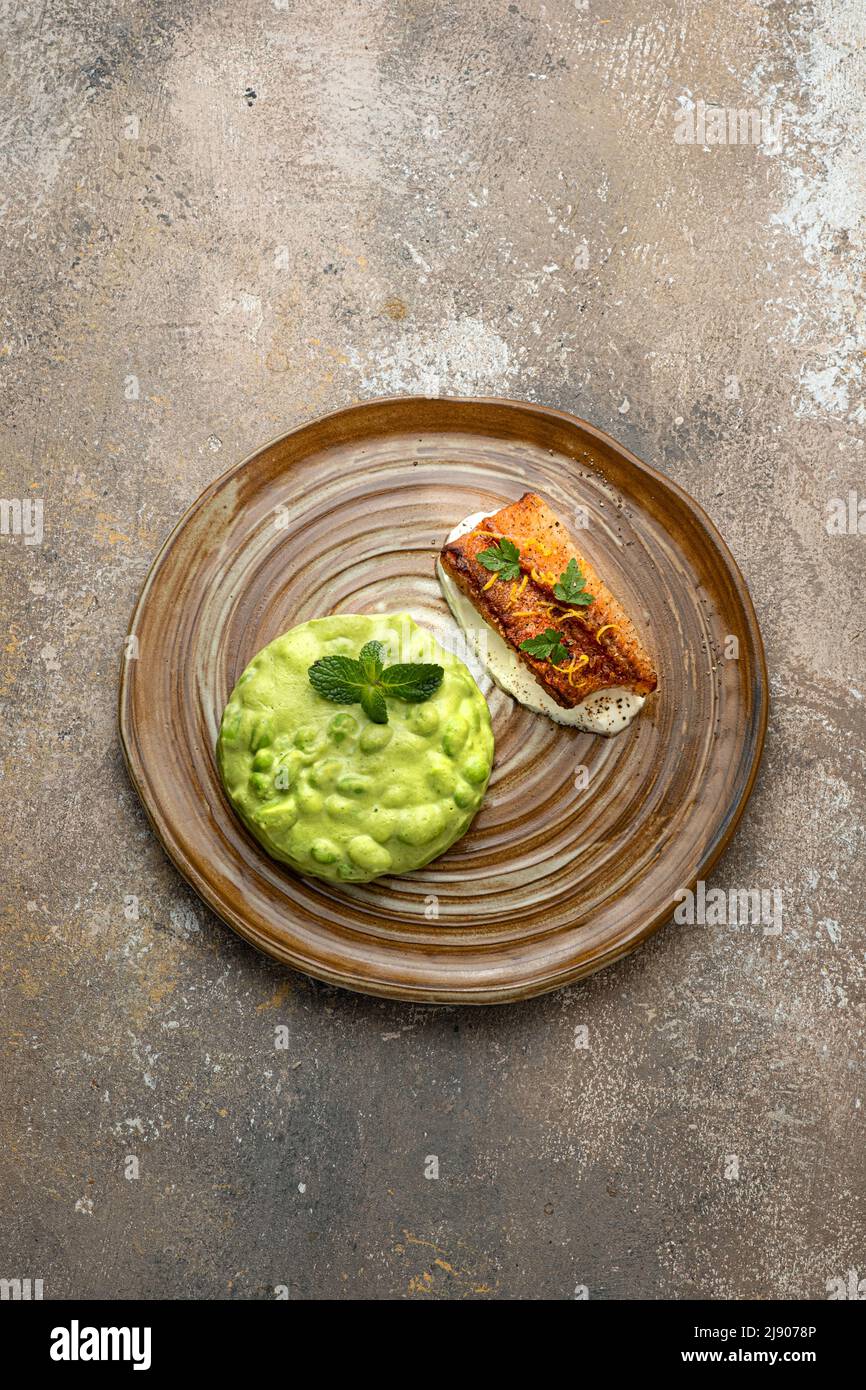 Pan seared white fish fillet with edamame puree on rustic background ...