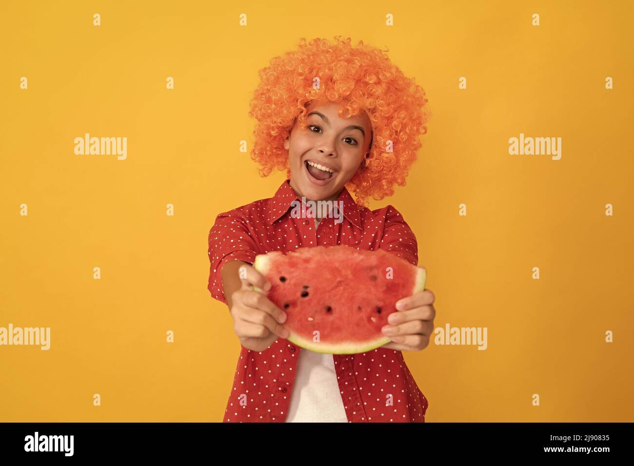 amazed kid in fancy orange hair wig holding fresh ripe water melon ...