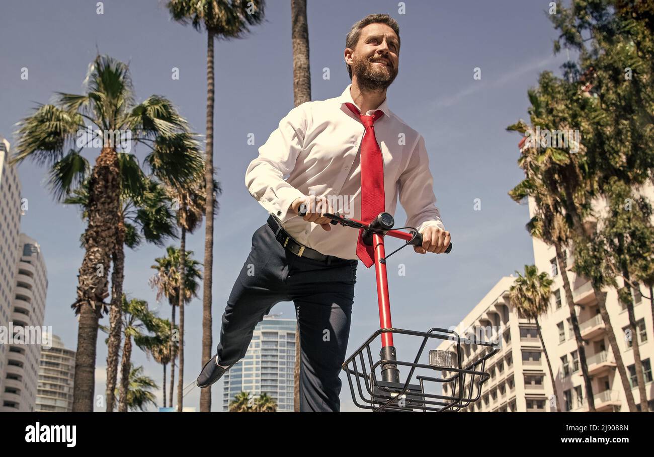 A new way of scooting around. Happy guy ride electric scooter on street ...