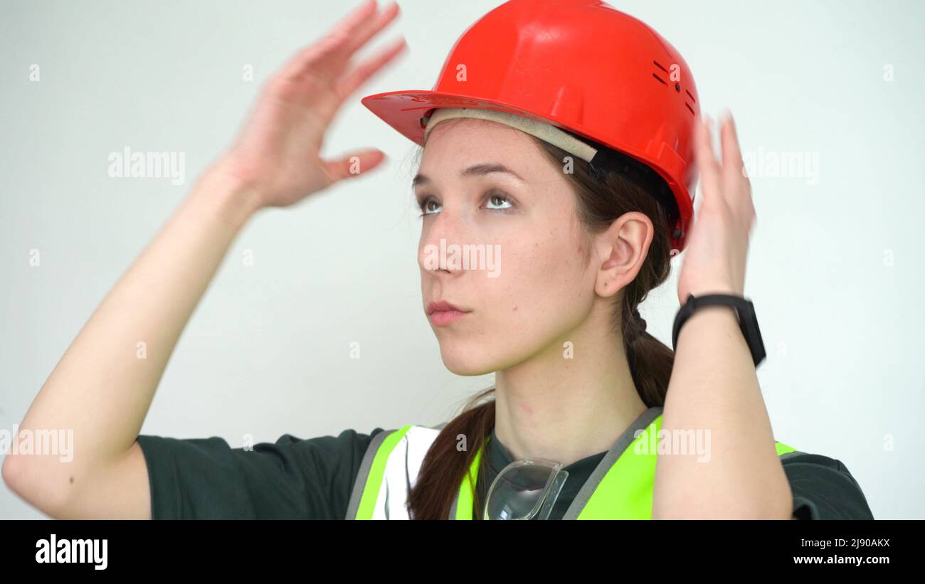 A young, beautiful, happy female construction worker gives a thumbs up ...