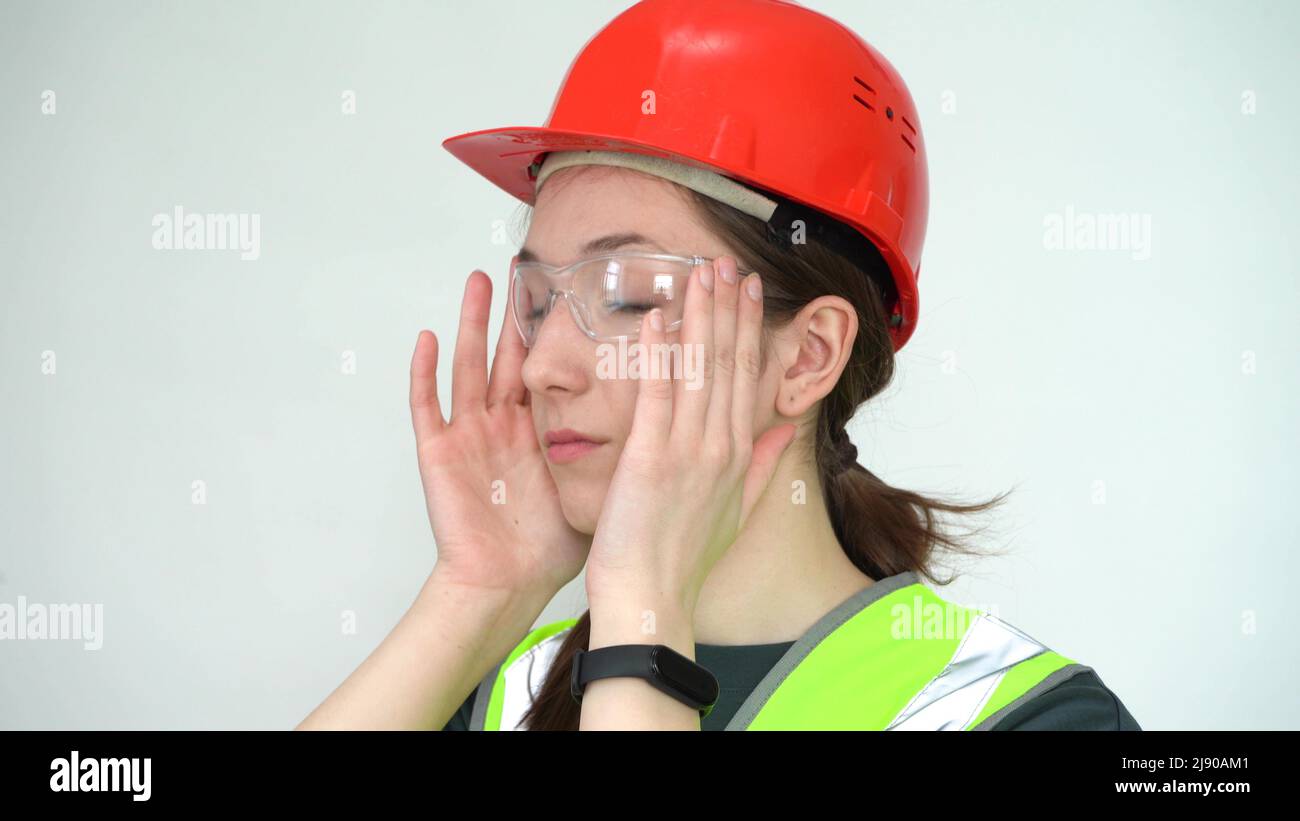 A young, beautiful, happy female construction worker gives a thumbs up ...
