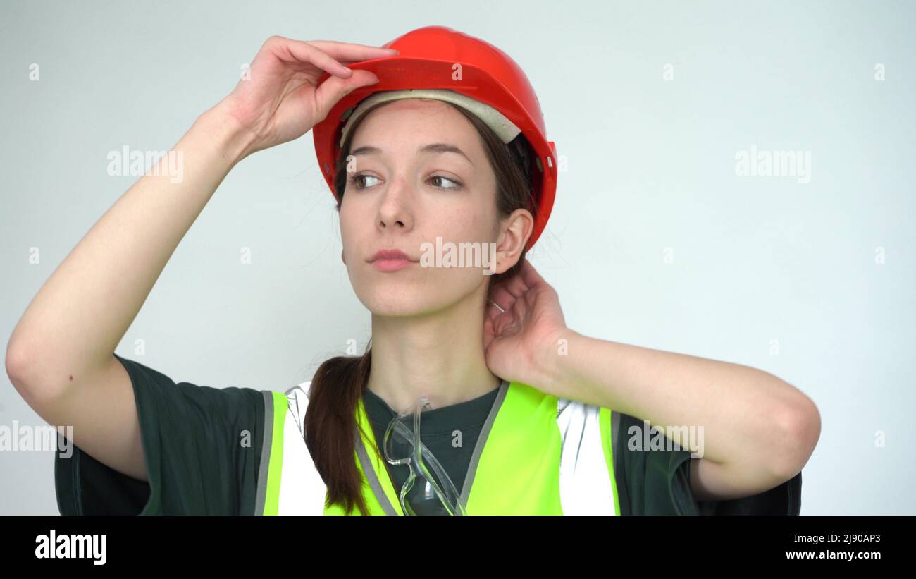 A young, beautiful, happy female construction worker gives a thumbs up ...