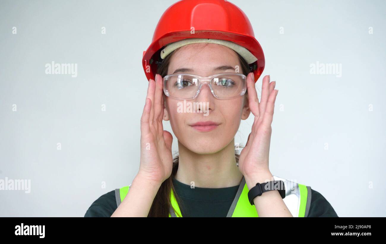 A young, beautiful, happy female construction worker gives a thumbs up ...