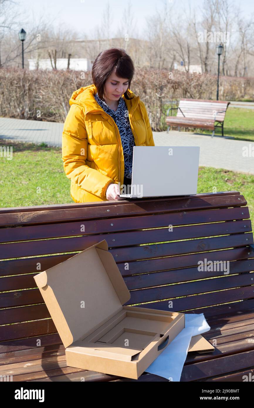 A brunette woman in a yellow warm jacket couldn't stand unpacking a new ...