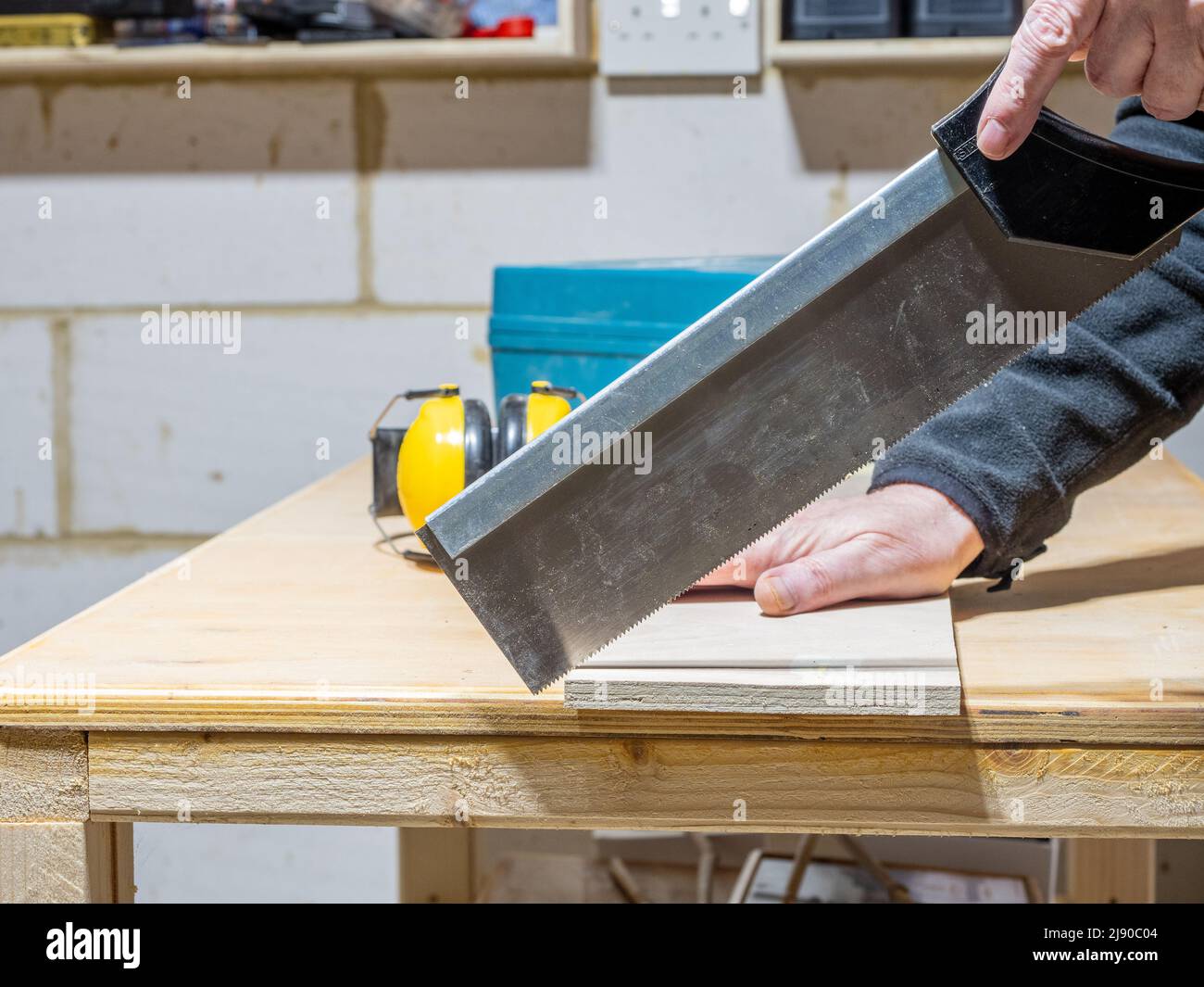 Carpenter trimming a construction joint on a plywood board using a ...