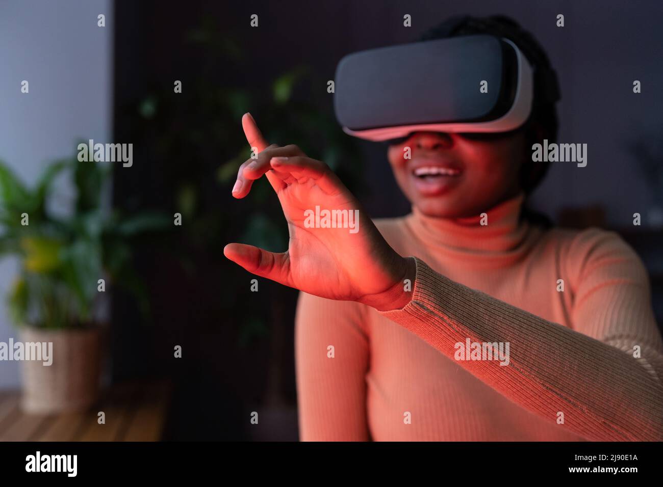 Joyful afro female touching virtual object with finger while working in ...