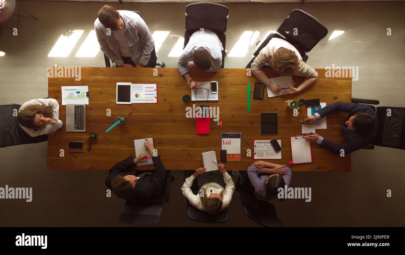 Aerial view of young people, co-workers during work process, meeting at ...