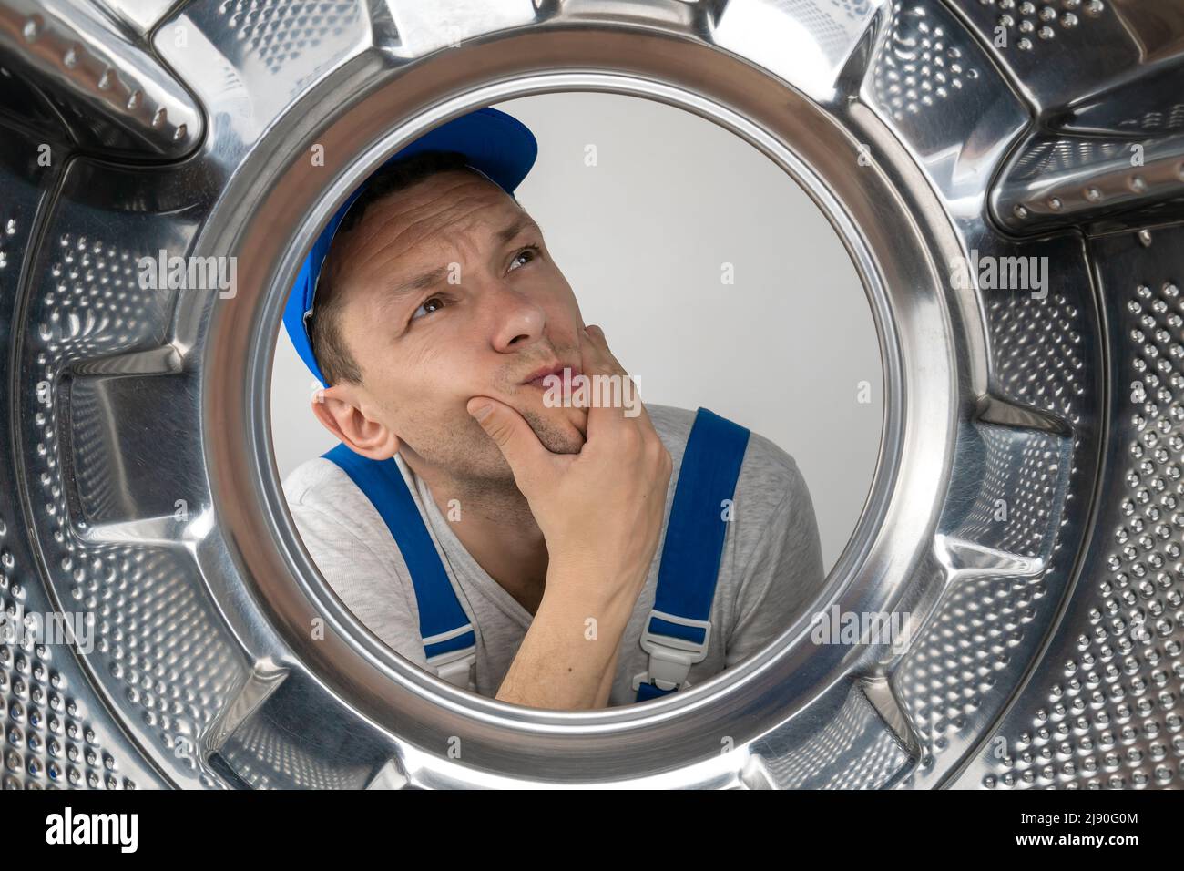 Male repairman in uniform holds his chin and looks thoughtfully to the ...