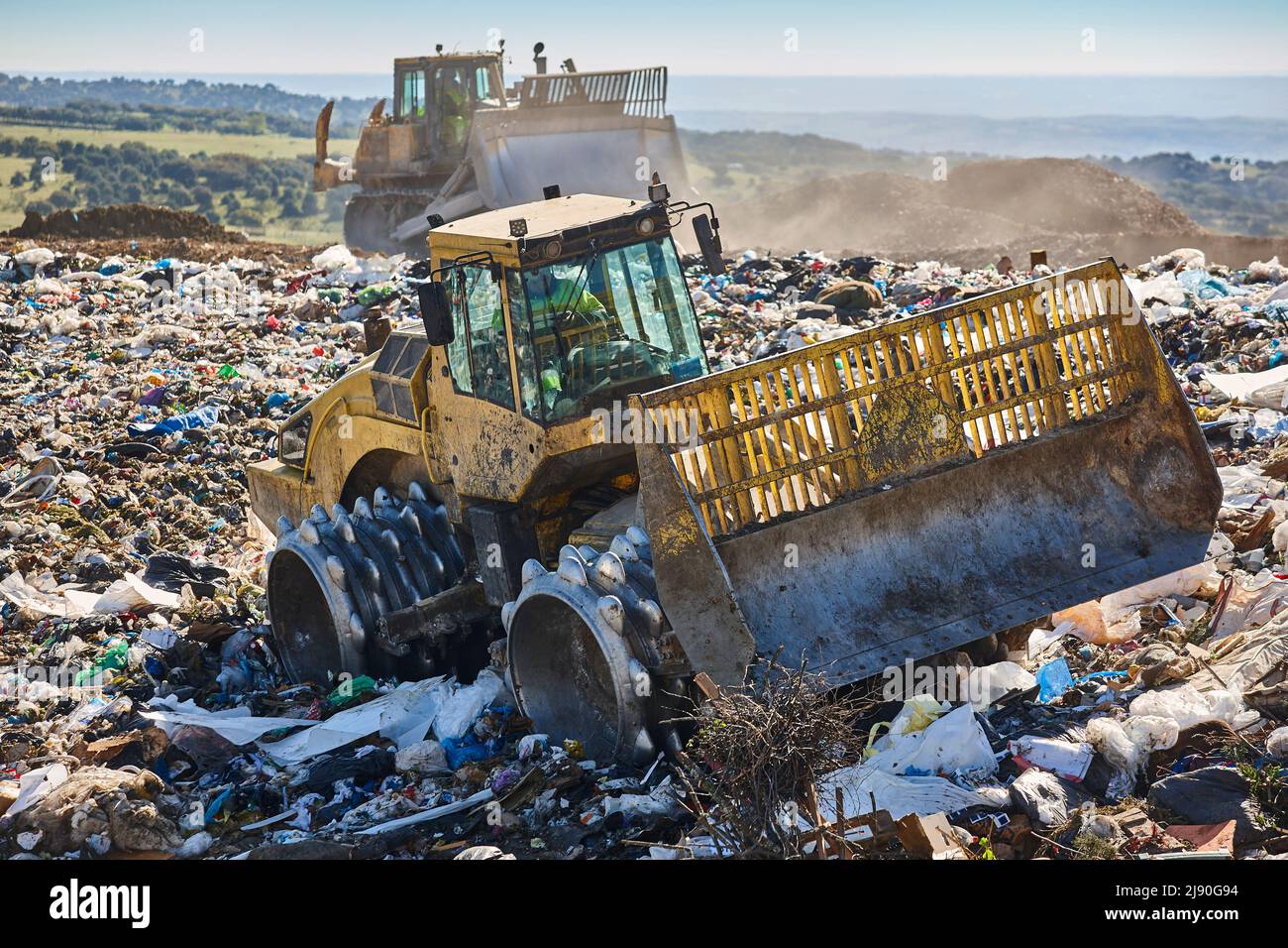 Heavy machinery shredding garbage in an open air landfill. Waste Stock ...