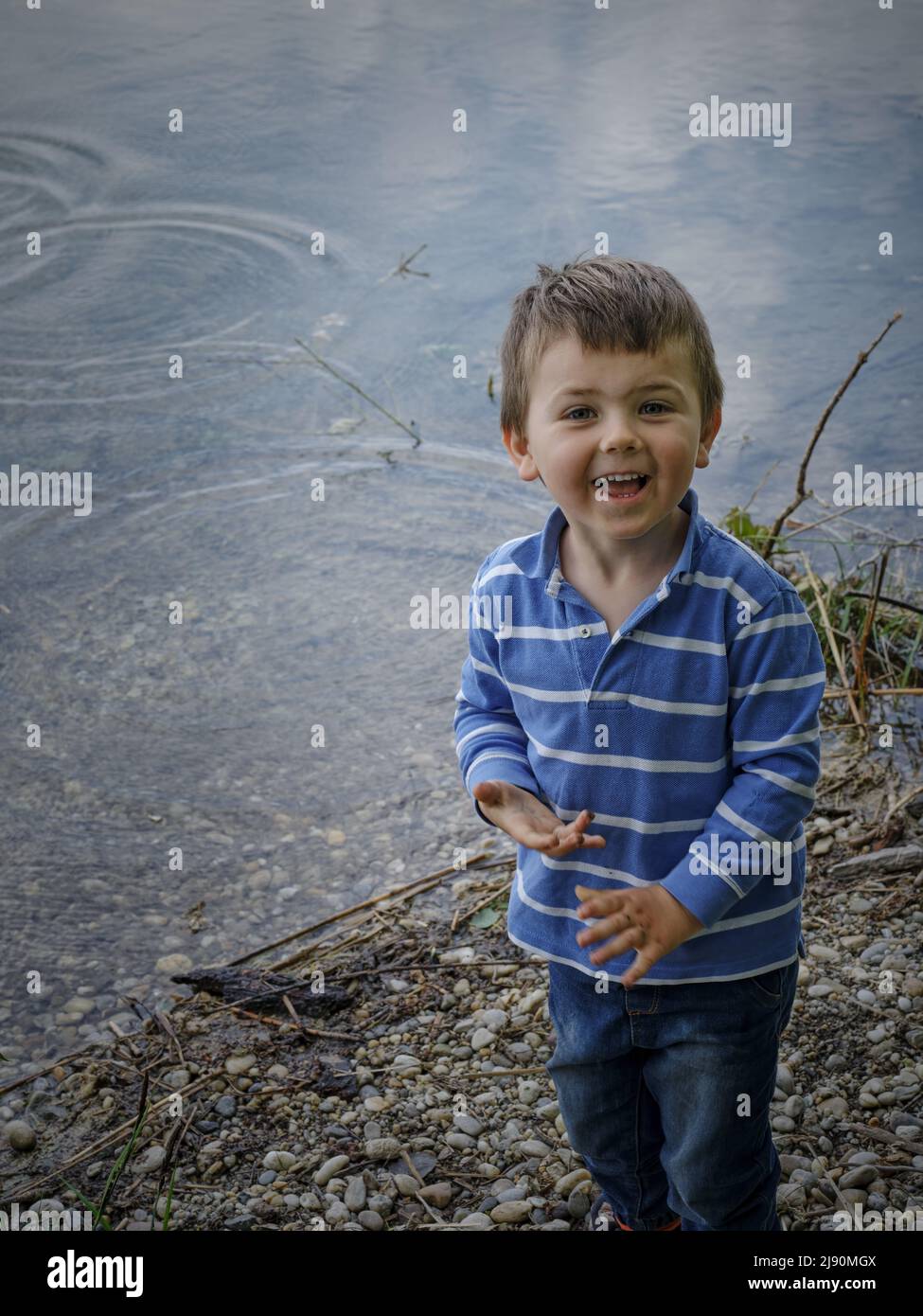 Happy smiling little boy after throwing pebbles into a pond Stock Photo ...