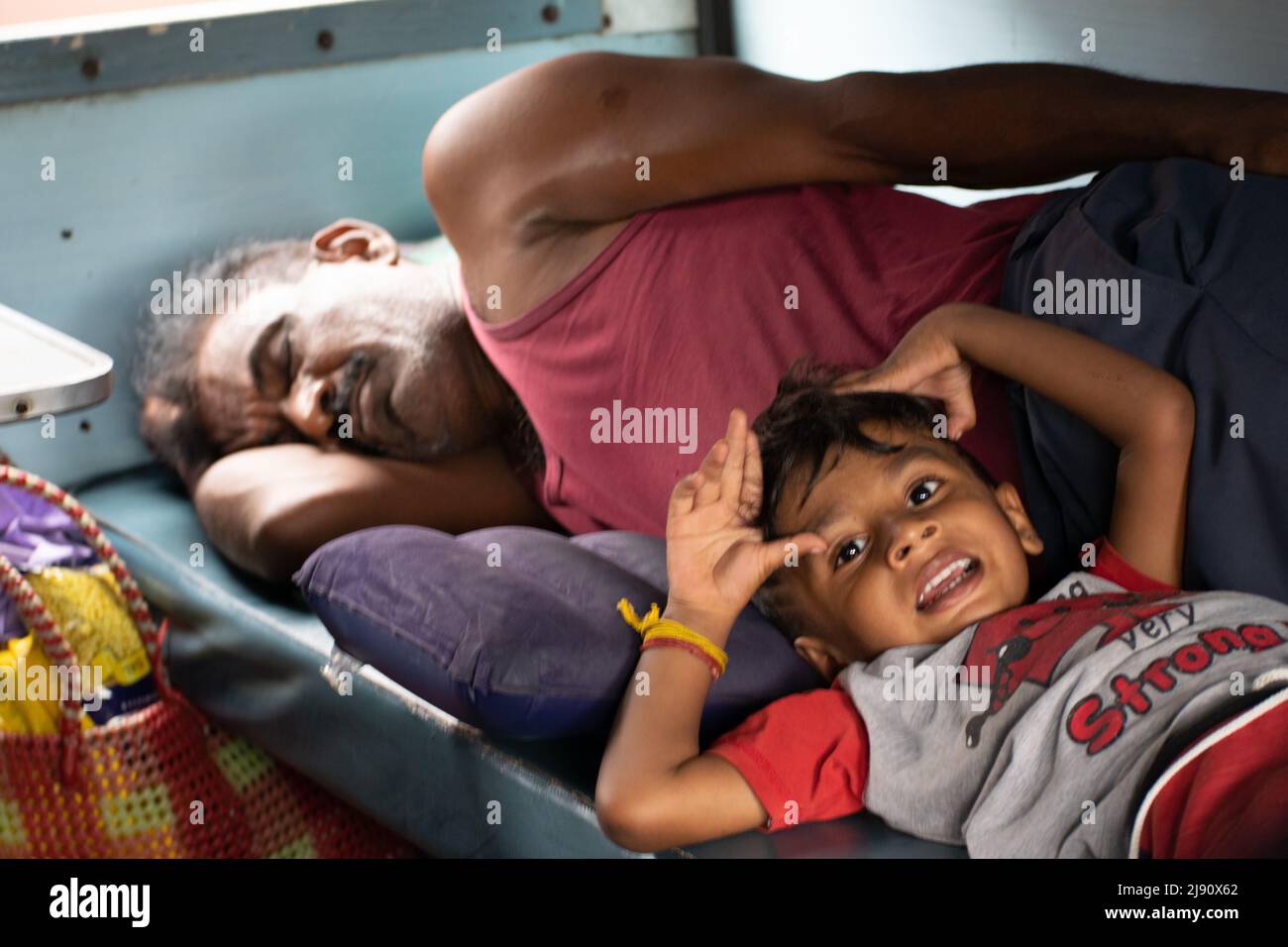 Indian boy sleeping with his father in train Stock Photo - Alamy