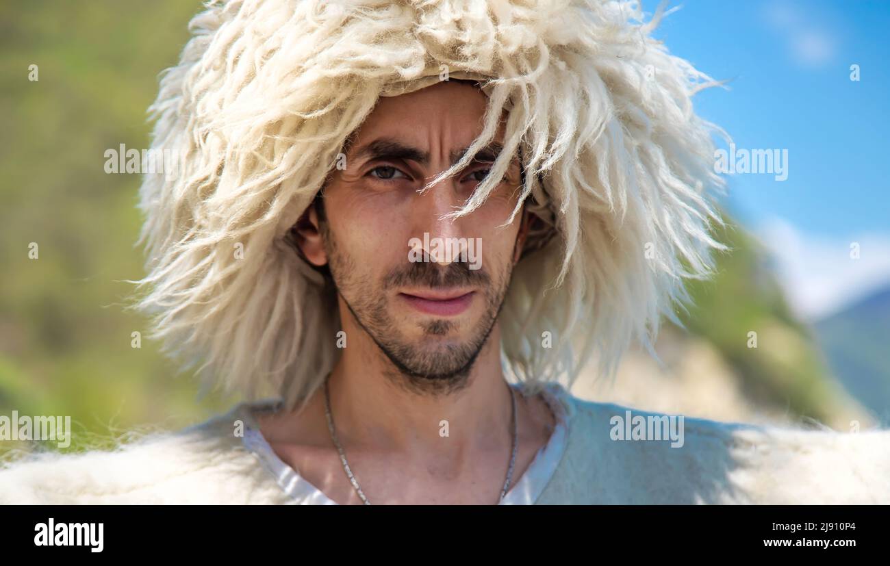 A Georgian man in a hat against the background of mountains and the sky ...