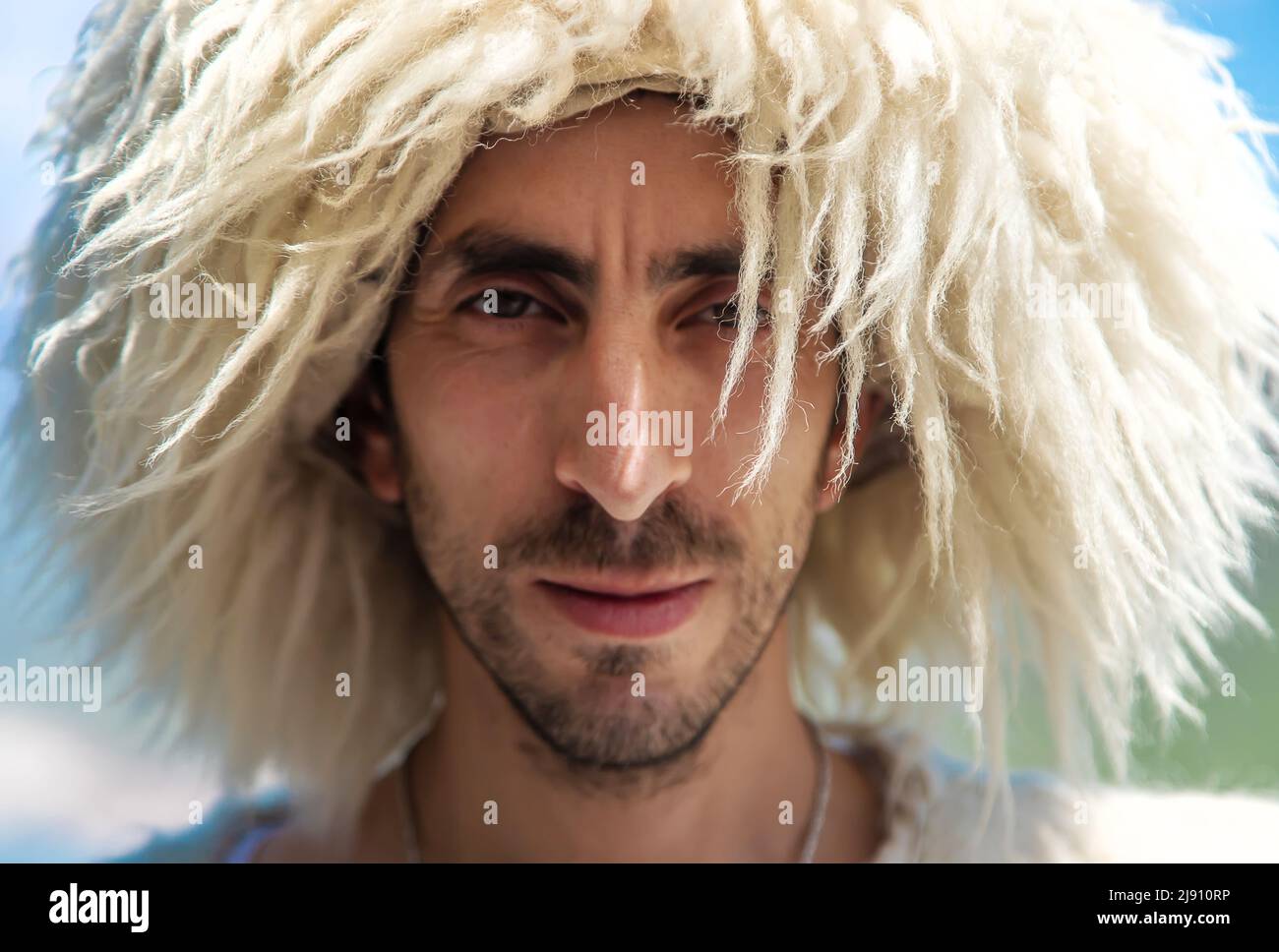 A Georgian man in a hat against the background of mountains and the sky ...
