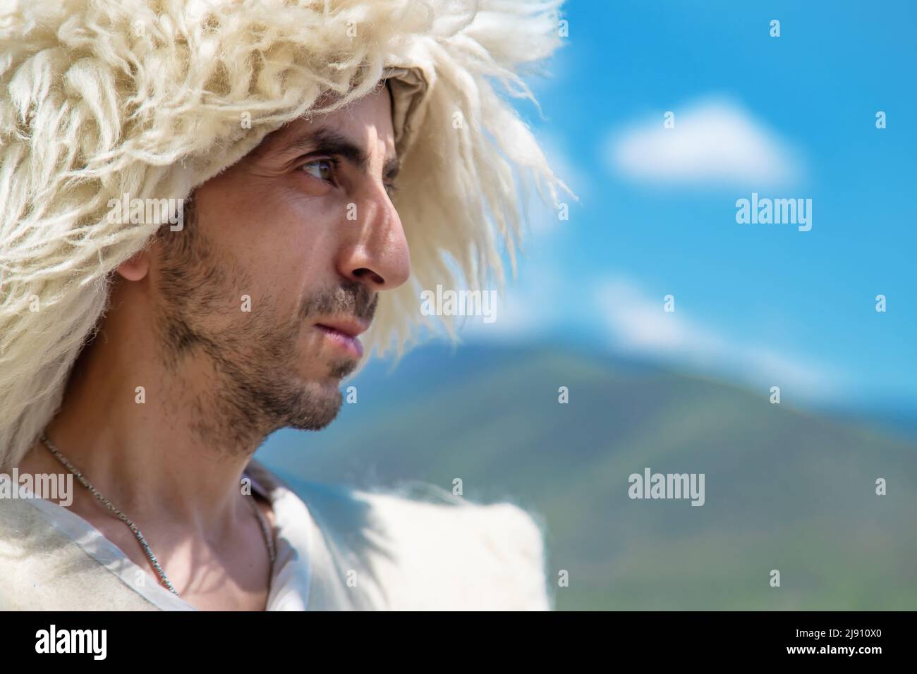 A Georgian man in a hat against the background of mountains and the sky ...
