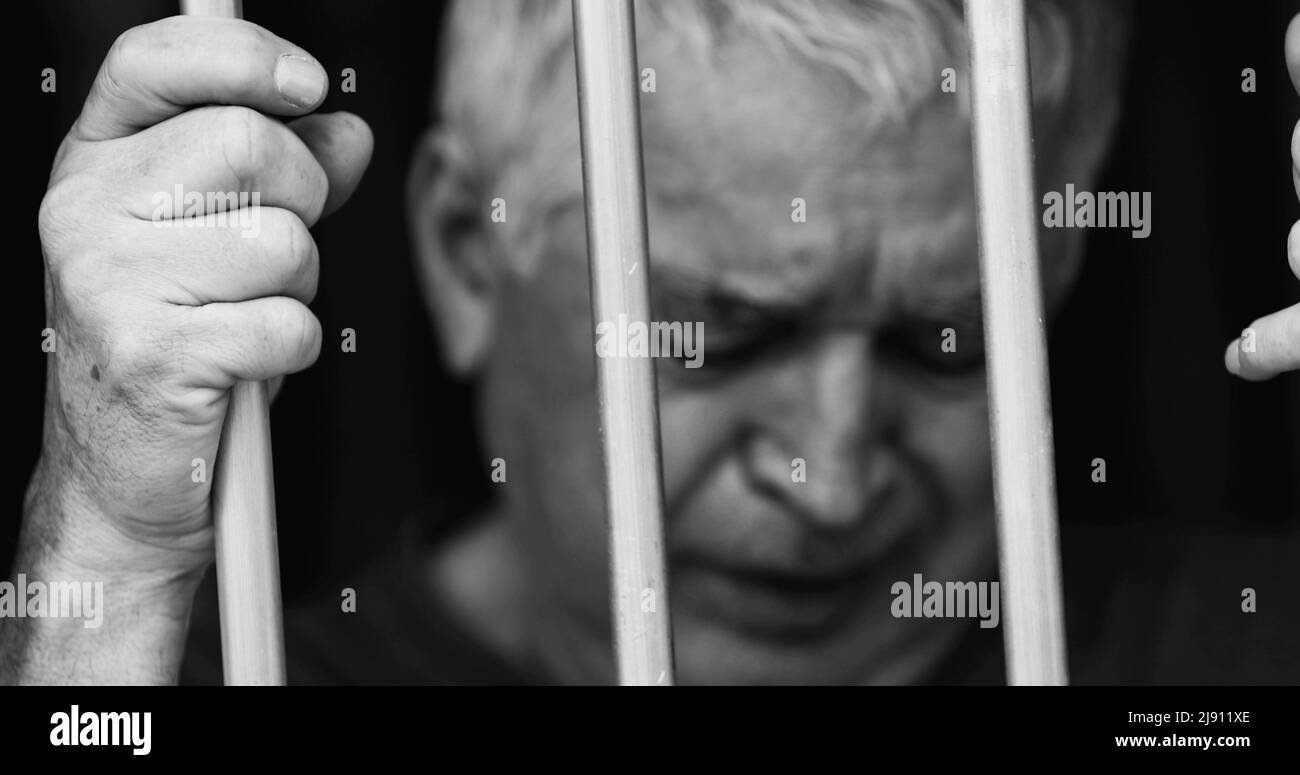 Desperate man locked behind bars Stock Photo - Alamy