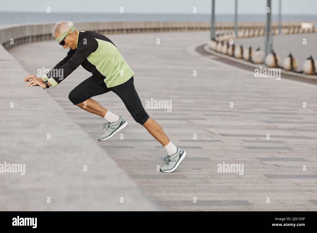 Horizontal side view shot of sporty senior man doing morning aerobic ...