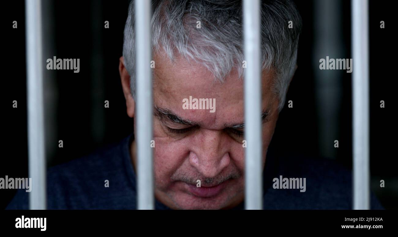 Older man feeling trapped holding into iron gate. Senior holds on bar ...