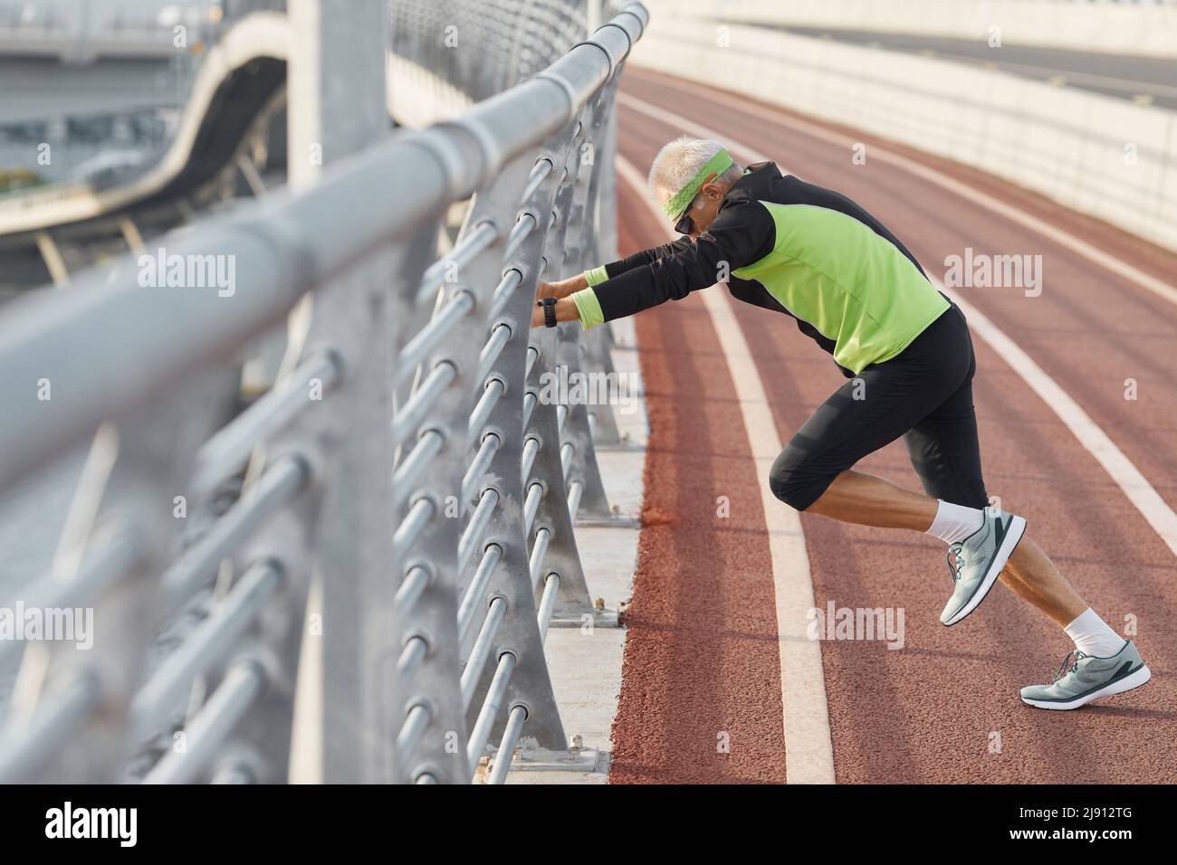 Horizontal side view of modern senior man wearing tracksuit doing ...