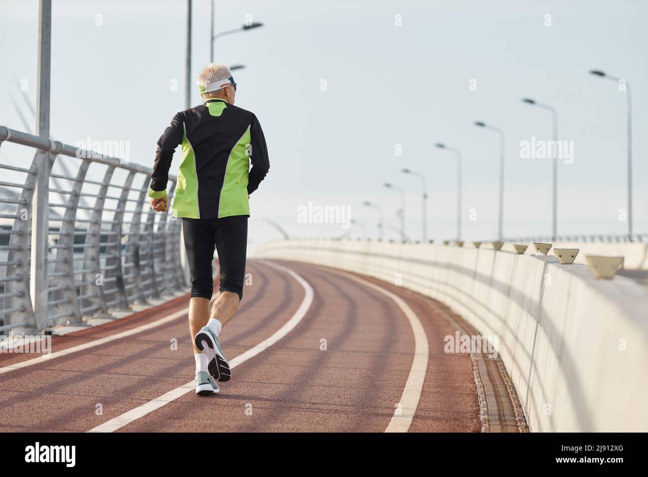 Horizontal back view shot of senior man wearing black and green ...