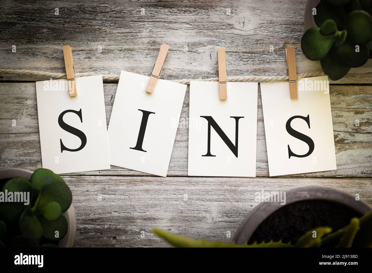 A set of printed cards spelling the word SINS on an aged wooden ...