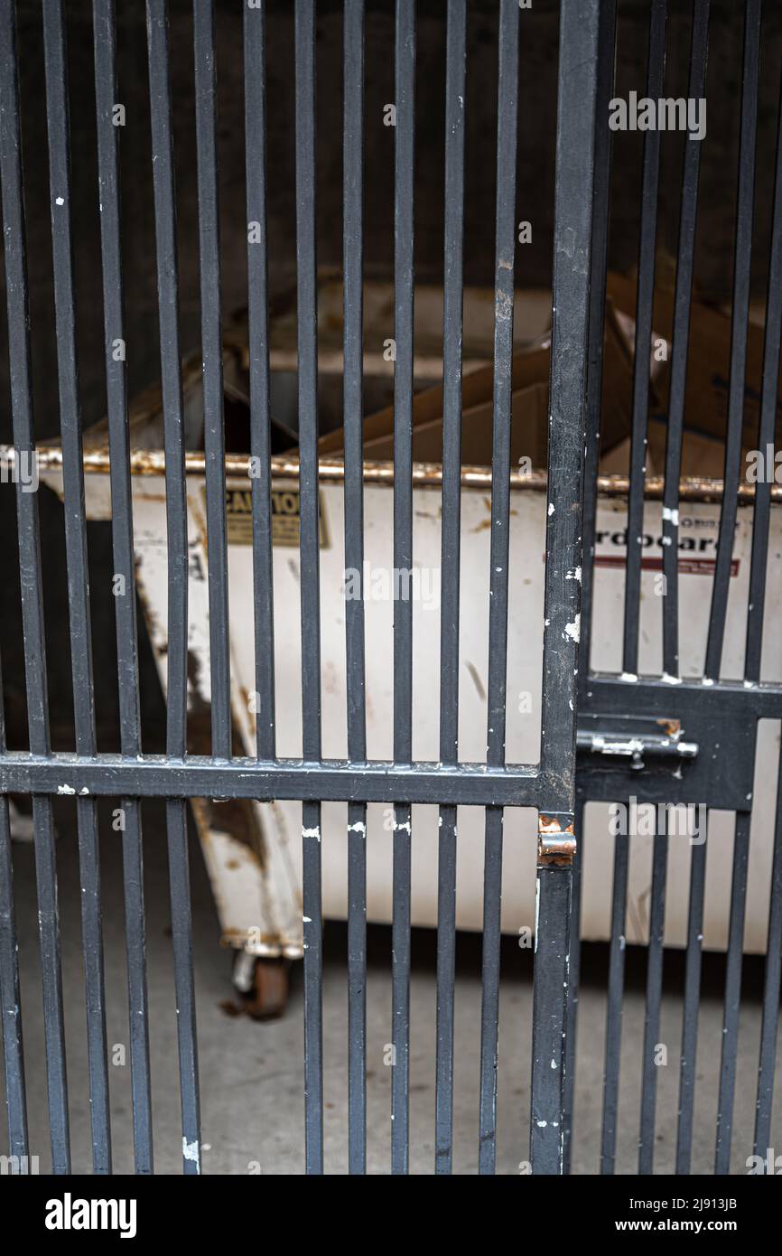 Trash Container Behind Metal Bars Stock Photo - Alamy